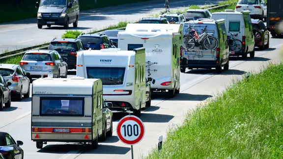 Zahlreiche Wohnmobile, Wohnwagen und Autos stehen im Autobahn-Stau.