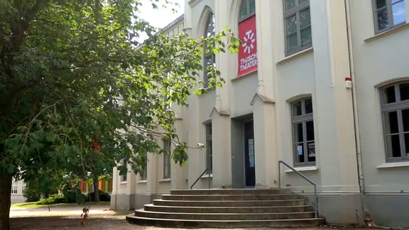 Das Thusch Theater in Teterow: Ein beiges, zweistöckiges Gebäude mit einer sechstufigen runden Treppe am Eingang.